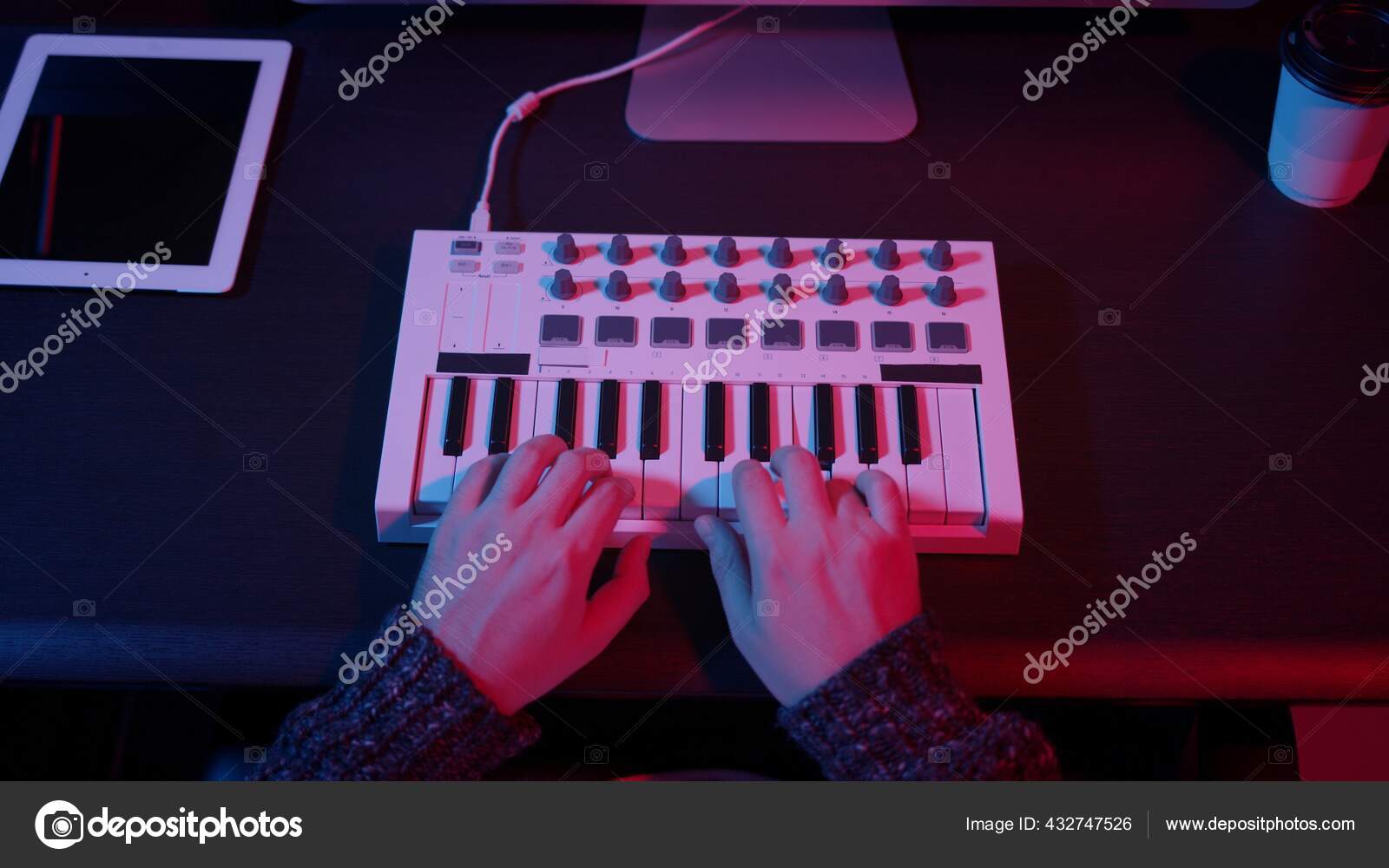 Top view of hands using midi keyboard in home studio with neon lights ...