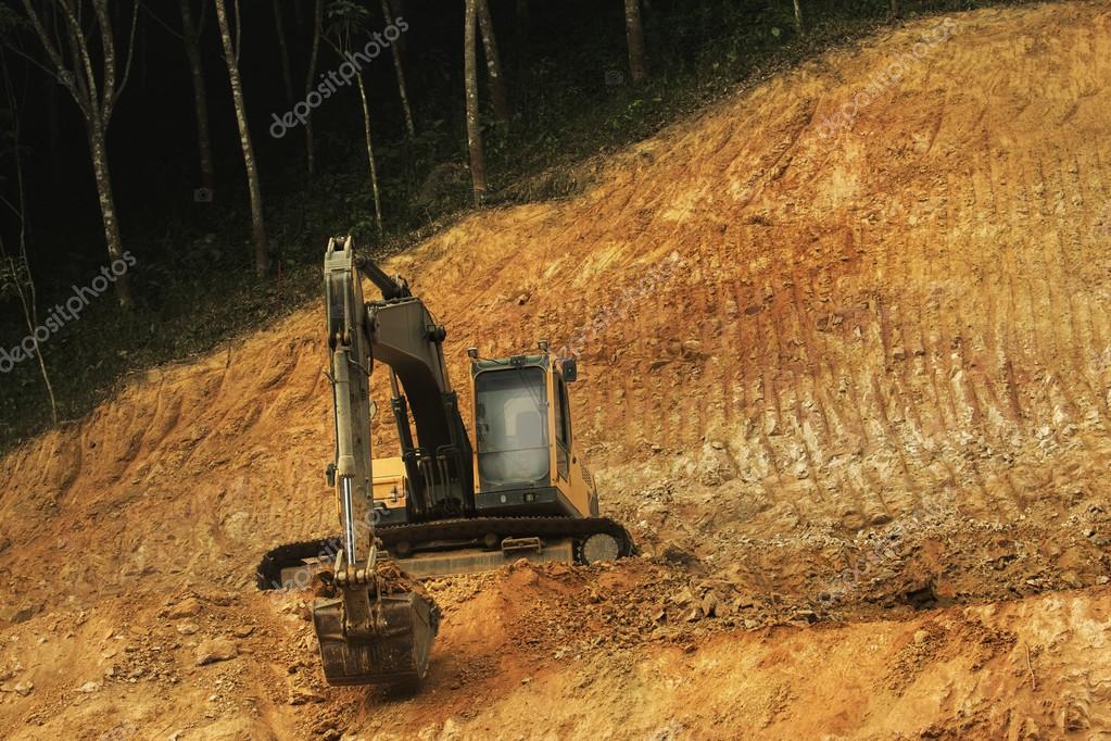 Heavy road construction machine working on hill slope Stock Photo by ...