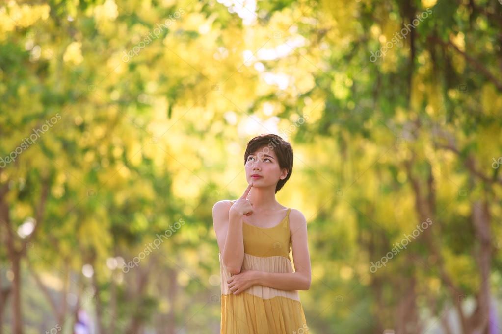 Portrait of beautiful young asian woman thinking against yellow — Stock ...