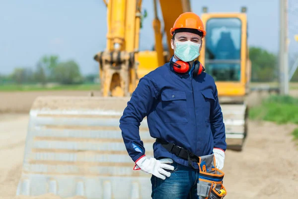 Portrait of masked worker in a construction site, covid coronavirus ...