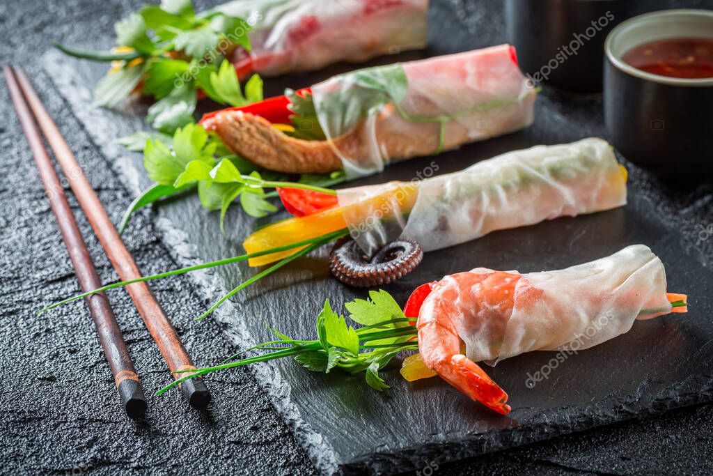 Deliciosos rollos de primavera hechos de mariscos y verduras sobre roca ...