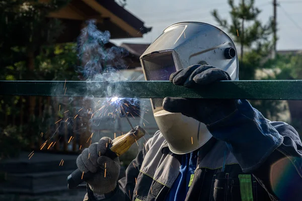 A strong man is a welder in a welding mask and welders leathers, a ...