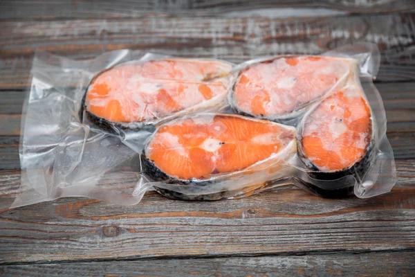 Frozen salmon fillets in a vacuum package wood table - Stock Image ...