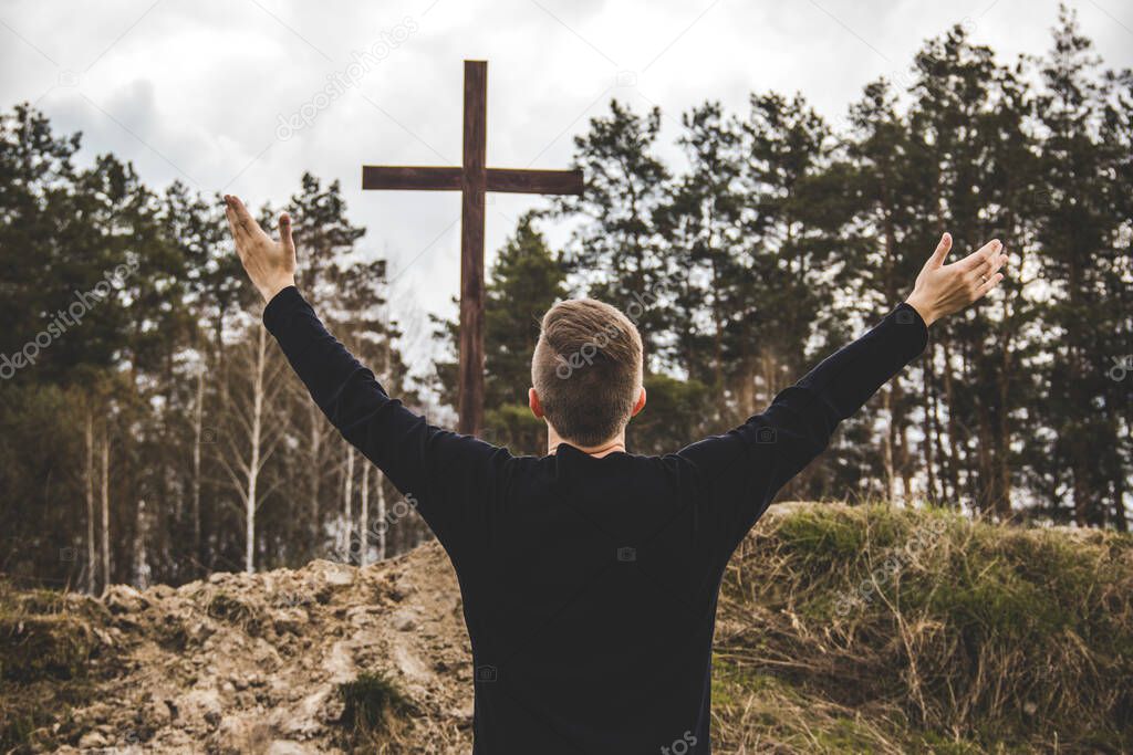 El hombre levantó sus manos y alaba a Dios. El hombre mira la cruz. El ...