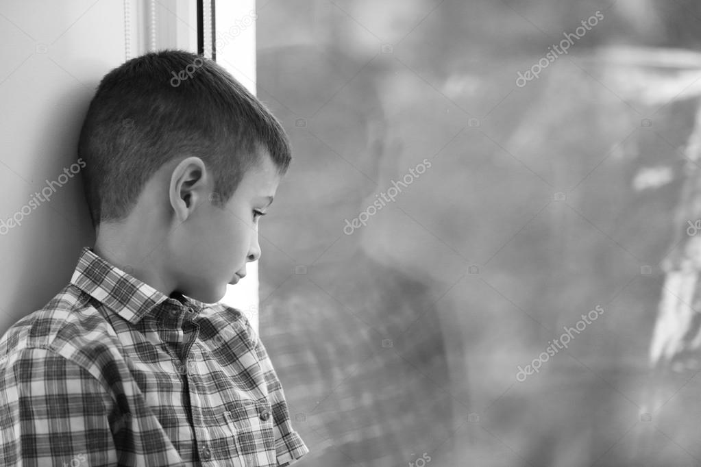 Sad boy sitting near window Stock Photo by ©belchonock 100502652