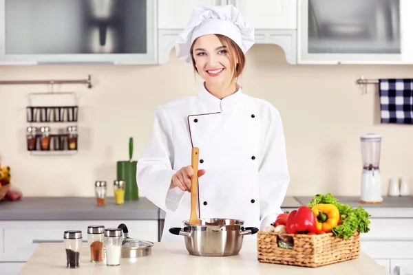 Young woman chef cooking in kitchen — Stock Photo © belchonock #19894923