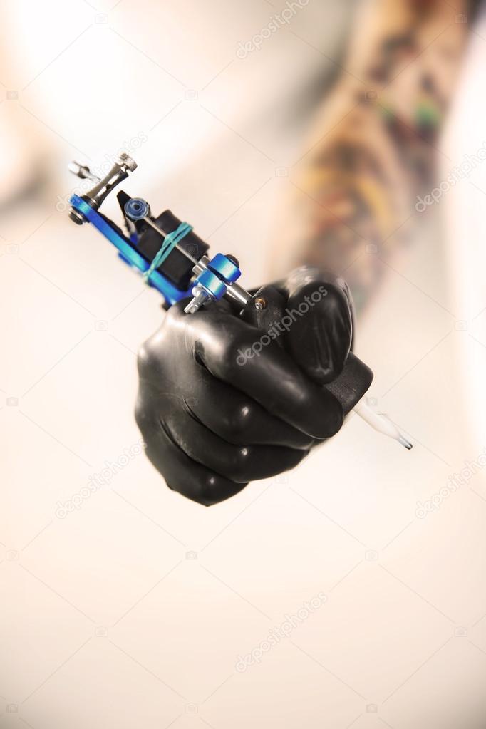 Man's hand holding tattoo machine Stock Photo by ©belchonock 110365846