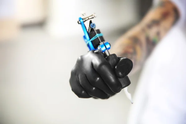 Man's hand holding tattoo machine Stock Photo by ©belchonock 110365846