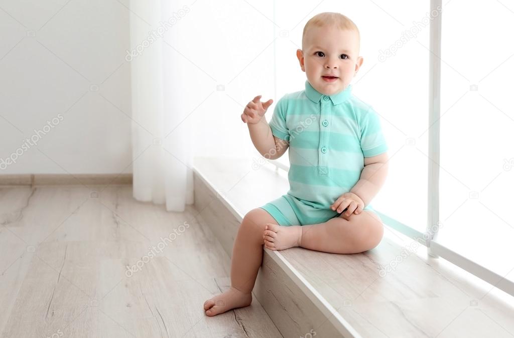 Baby boy sitting on the window Stock Photo by ©belchonock 114128528