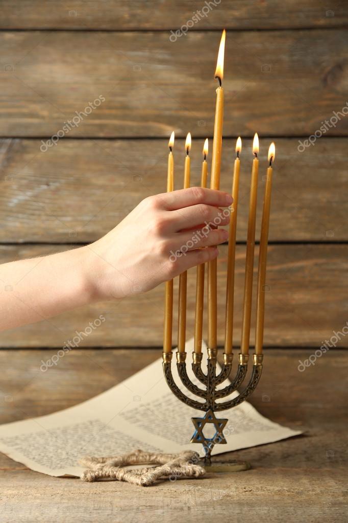 Hand burning candles on Menorah on wooden background Stock Photo by ...