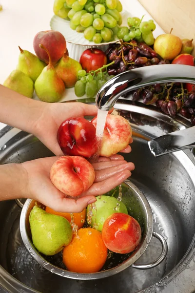 Woman's hands washing apple and other fruits in colander in sink Stock ...