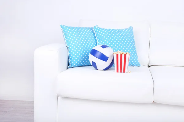 Popcorn and ball on sofa Stock Photo by ©belchonock 54032709
