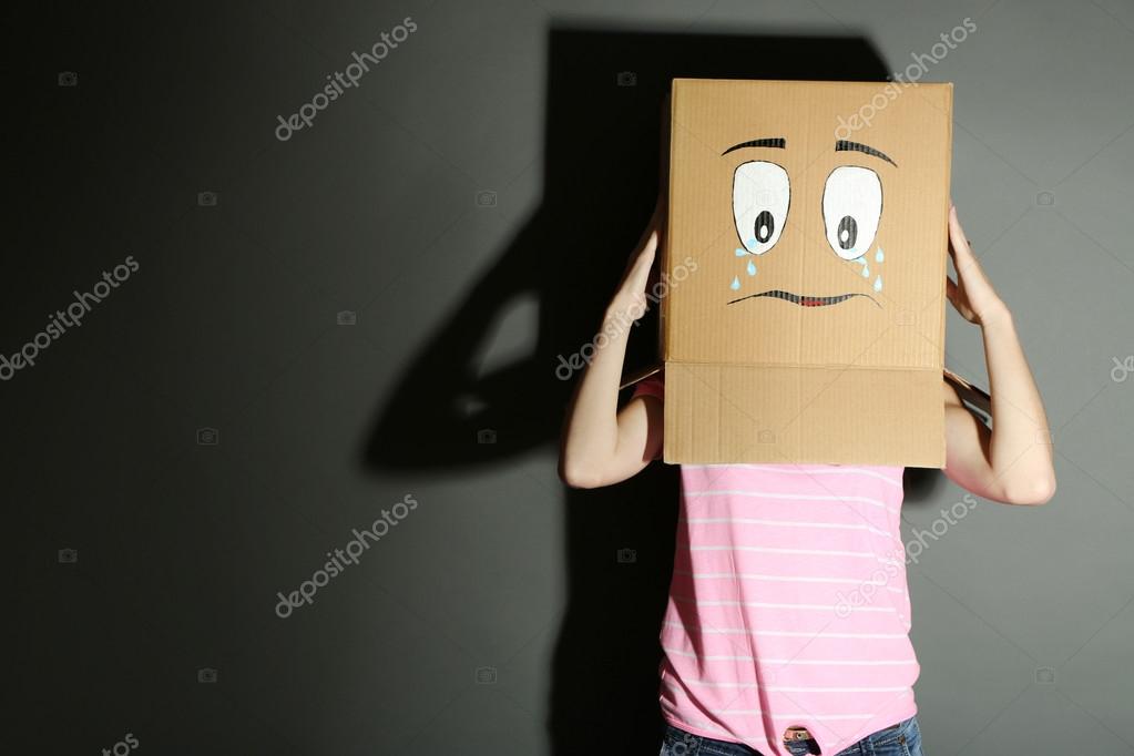 Woman with cardboard box on her head with sad face, on grey background ...