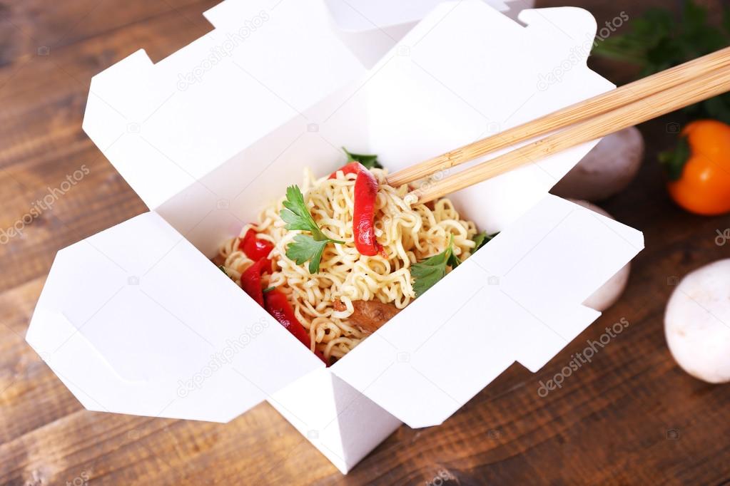 Chinese noodles in takeaway boxes with mushrooms and parsley on wooden ...