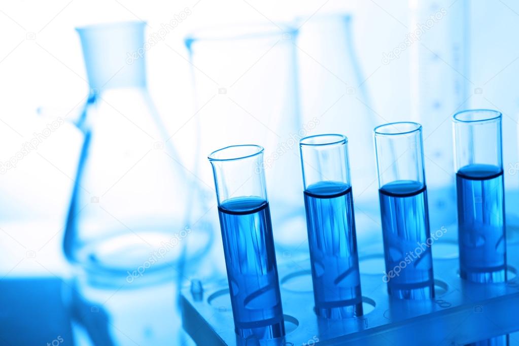 Transparent test-tubes with blue water and flasks on light background ...