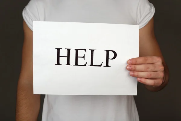 Sheet of paper with Help sign in male hand on dark background Stock ...