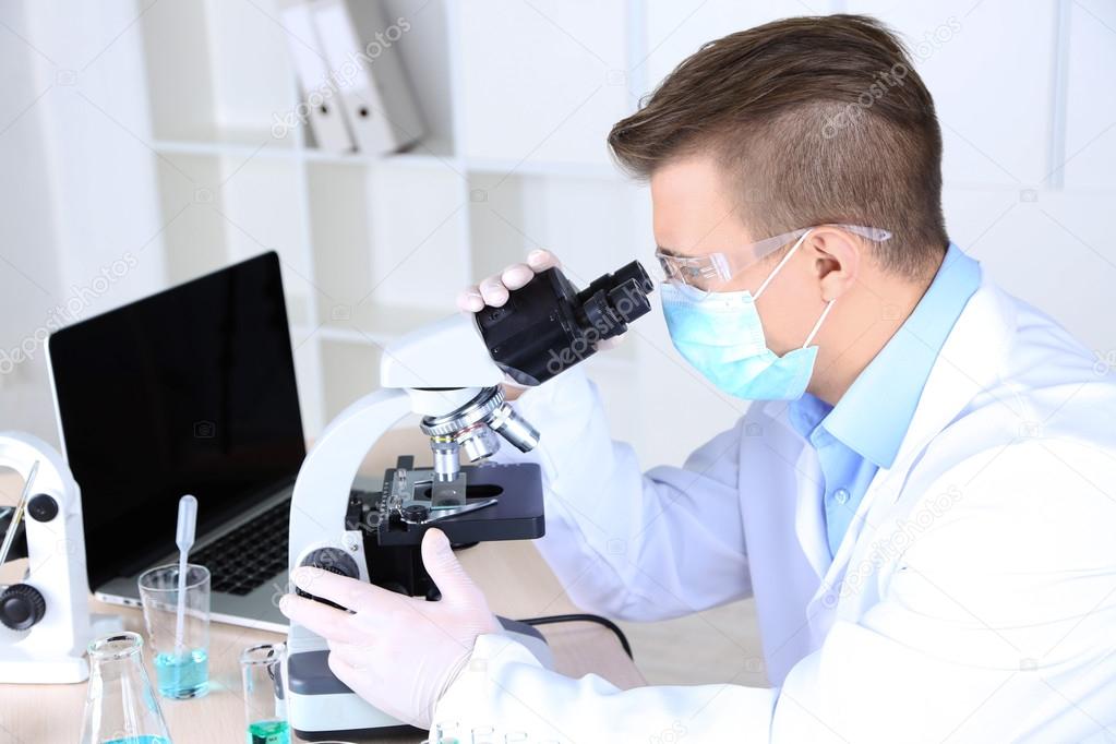 Male scientist using microscope in laboratory Stock Photo by ...
