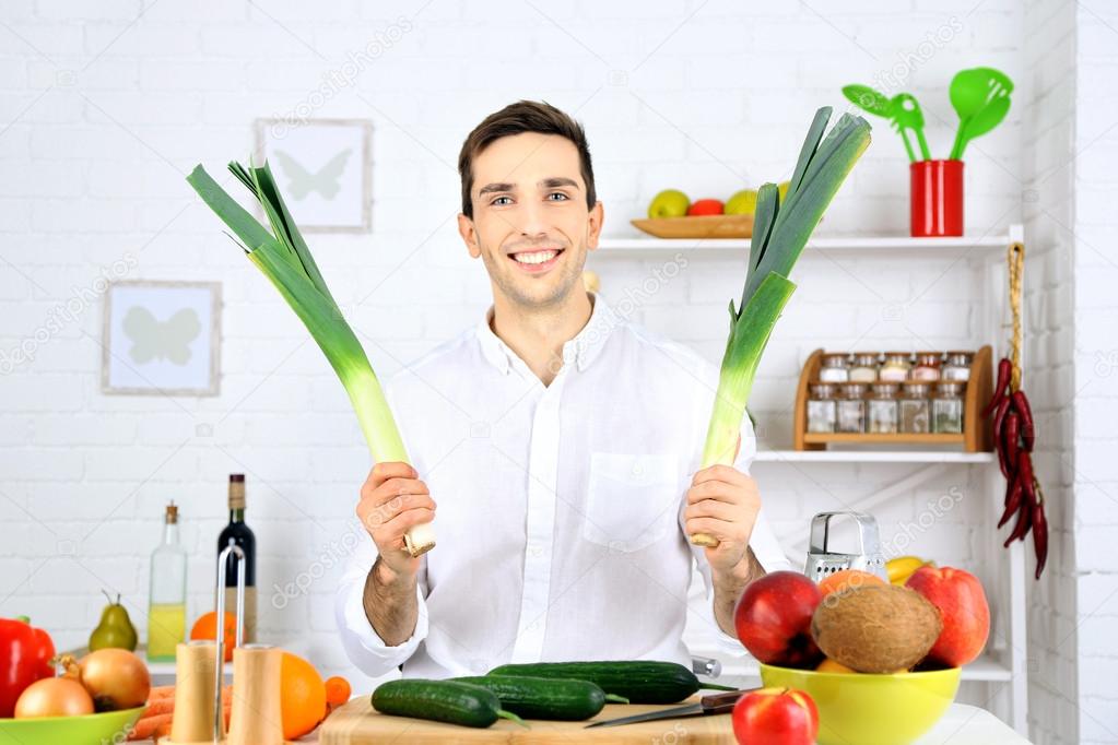Man at table with different products in kitchen on white wall ...