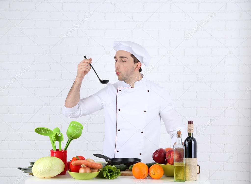 Chef at table with different products and utensil in kitchen on white ...