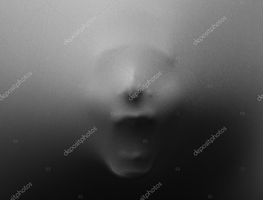 Screaming human face pressing through fabric as horror background ...