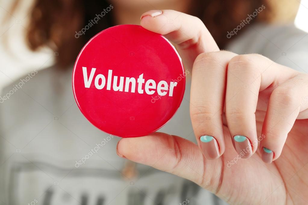Round volunteer button in hand close-up Stock Photo by ©belchonock 67940569