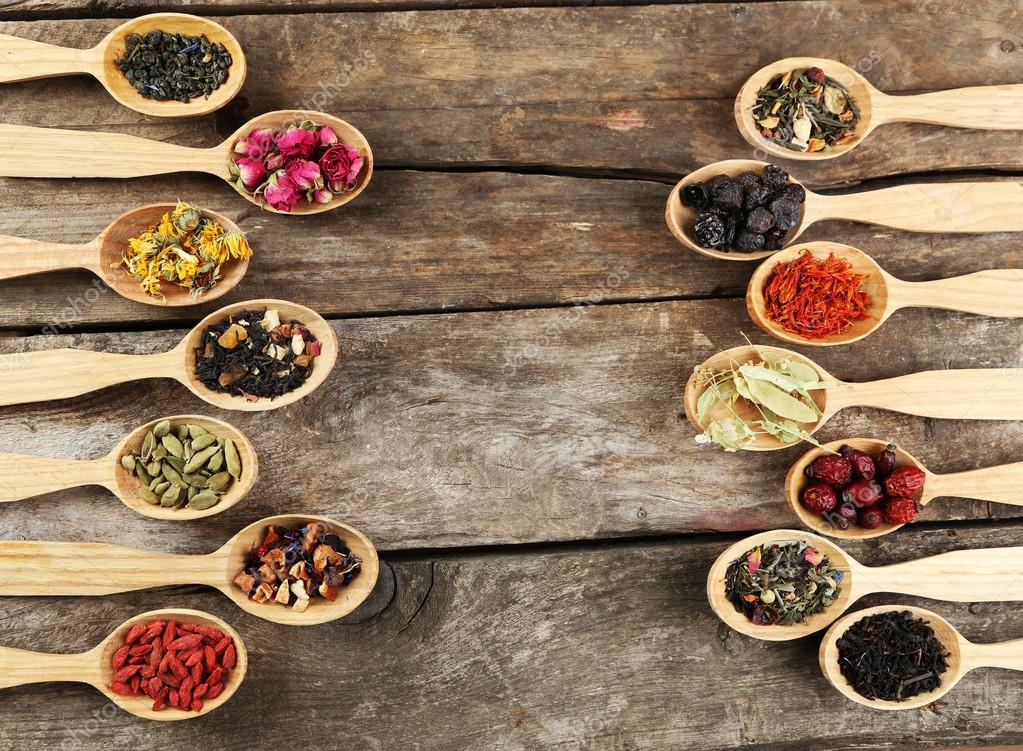 Collection of tea and natural additives in wooden spoons, on old wooden ...