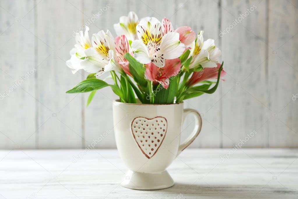 Beautiful flowers in cup, on wooden background Stock Photo by ...