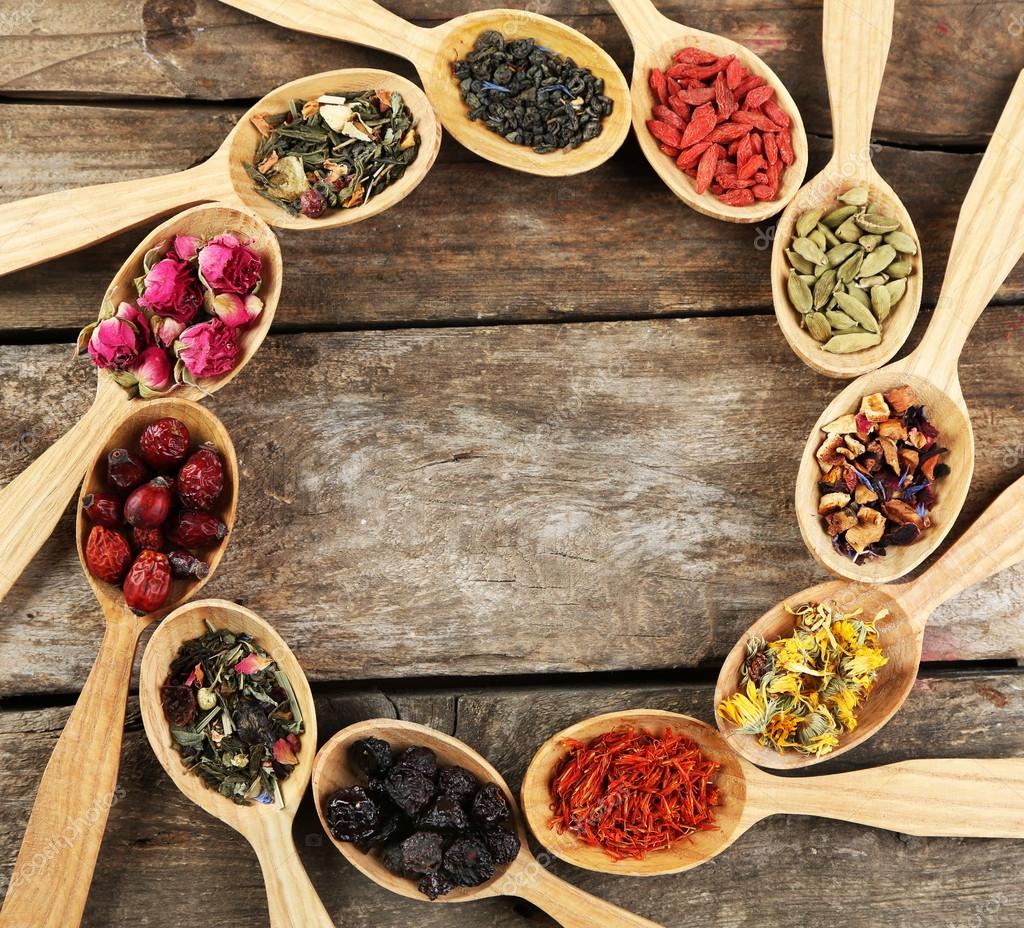 Collection of tea and natural additives in wooden spoons, on old wooden ...