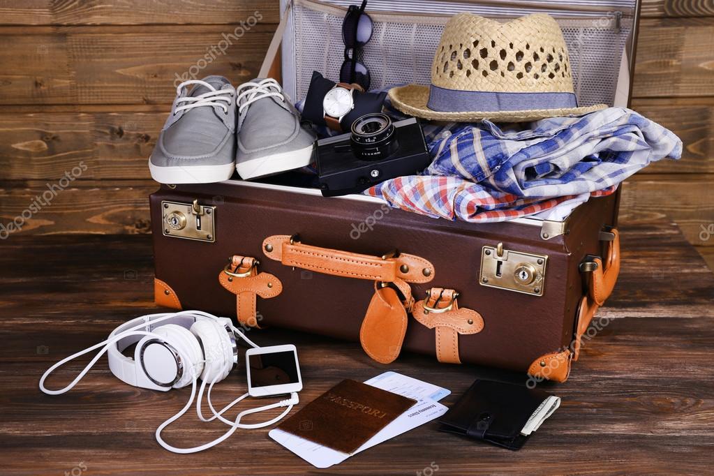 Packed suitcase of vacation items on wooden background Stock Photo by ...