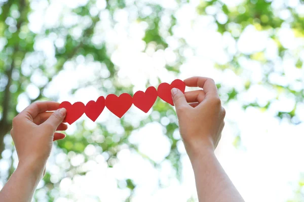 Hands holding string of paper hearts — Stock Photo © graphicphoto #53989987