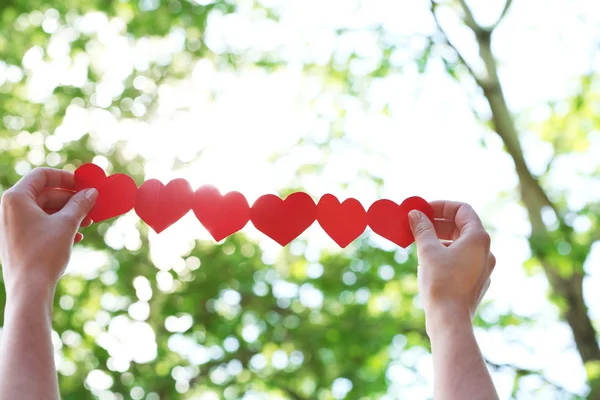 Hands holding string of paper hearts — Stock Photo © graphicphoto #53989987