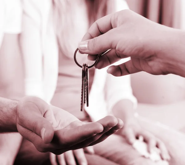 Real estate agent giving keys to young couple, closeup Stock Photo by ...