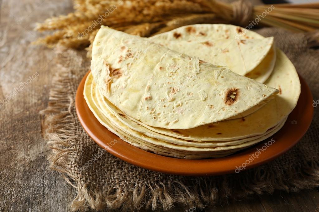 Stack of homemade whole wheat flour tortilla on plate, on wooden table ...