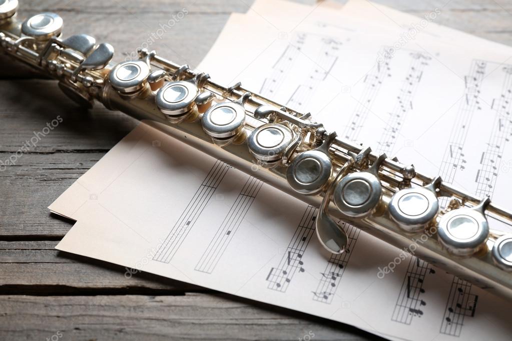 Silver flute with music notes on wooden table close up — Stock Photo ...