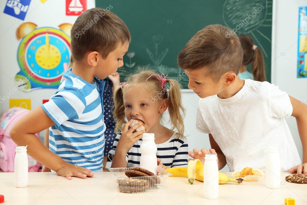 Cute children at lunch time in classroom Stock Photo by ©belchonock ...