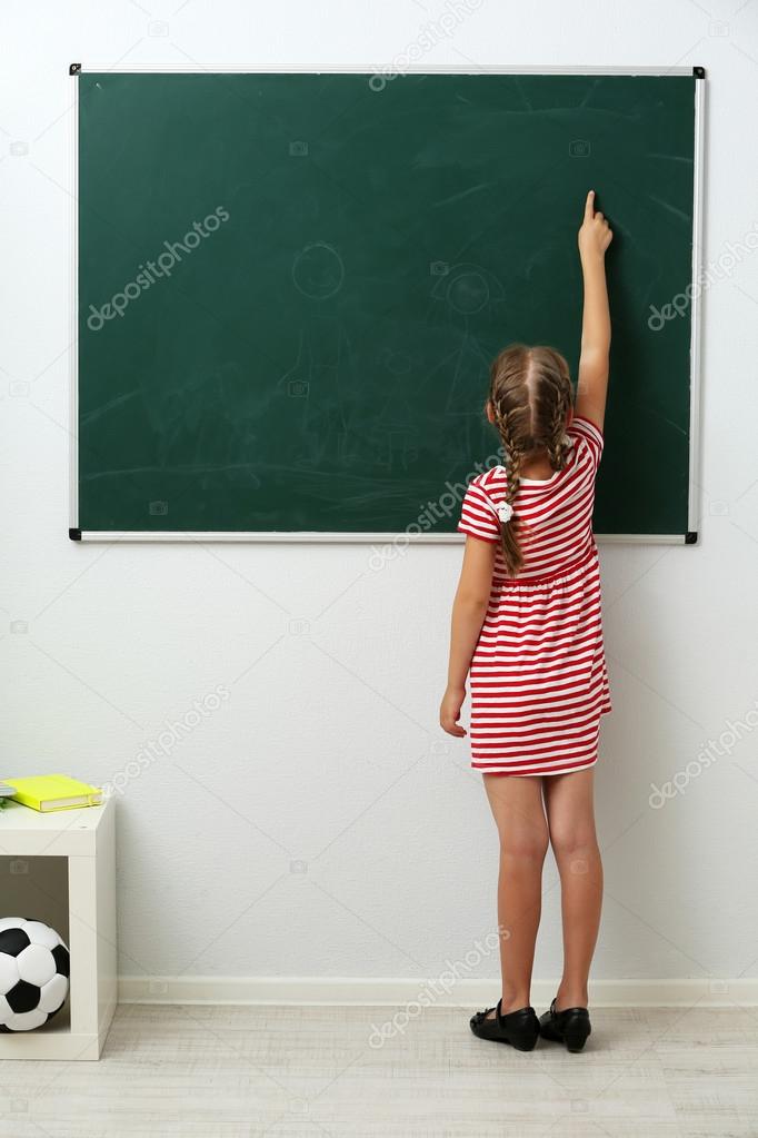 Little girl pointing at something at chalkboard Stock Photo by ...