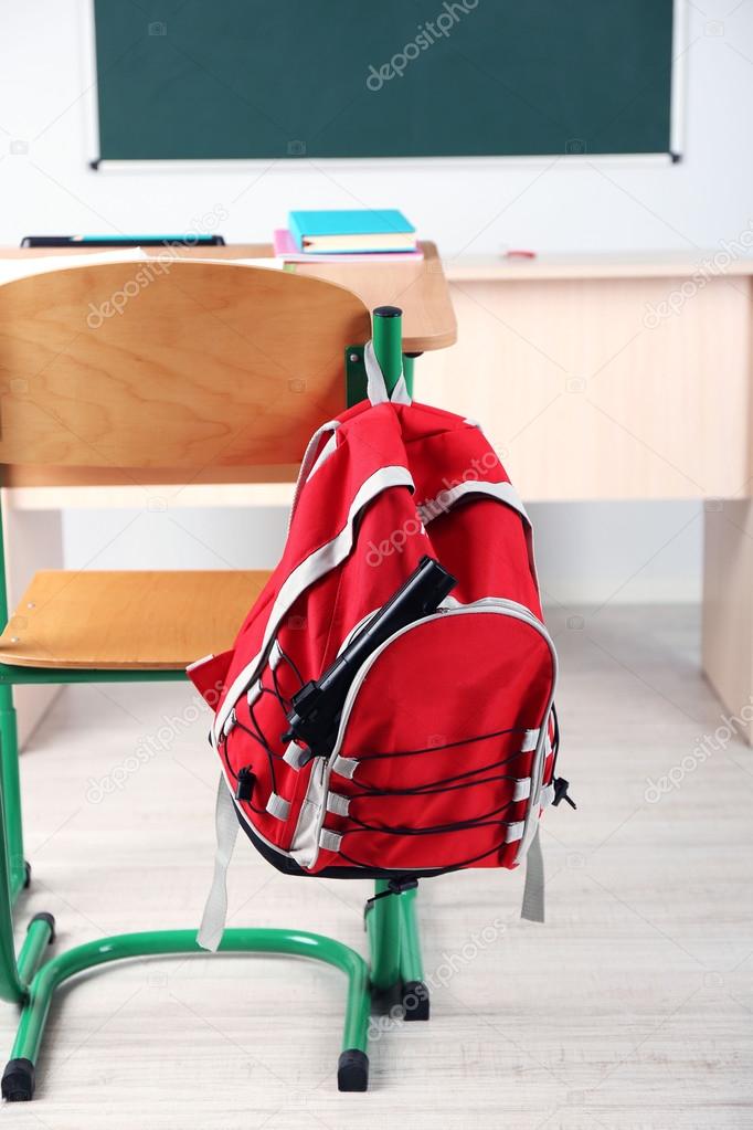 Backpack with gun in classroom — Stock Photo © belchonock #82449328