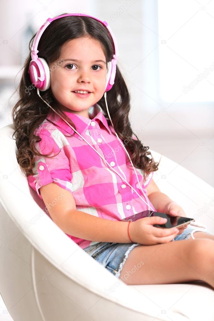 Attractive little girl sitting on chair — Stock Photo © belchonock #87847704