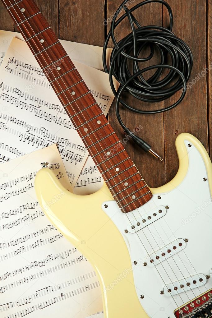 Electric guitar with musical notes on wooden background Stock Photo by ...