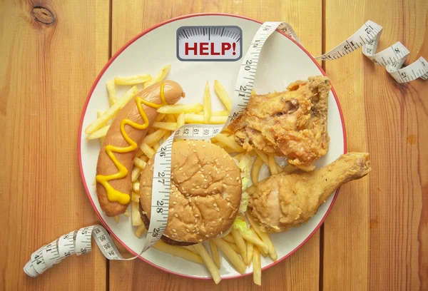 Junk food diet weighing scales Stock Photo by ©nupix 87371652