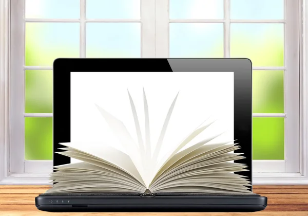 Black laptop and openned book on wooden table over window - Stock Image ...