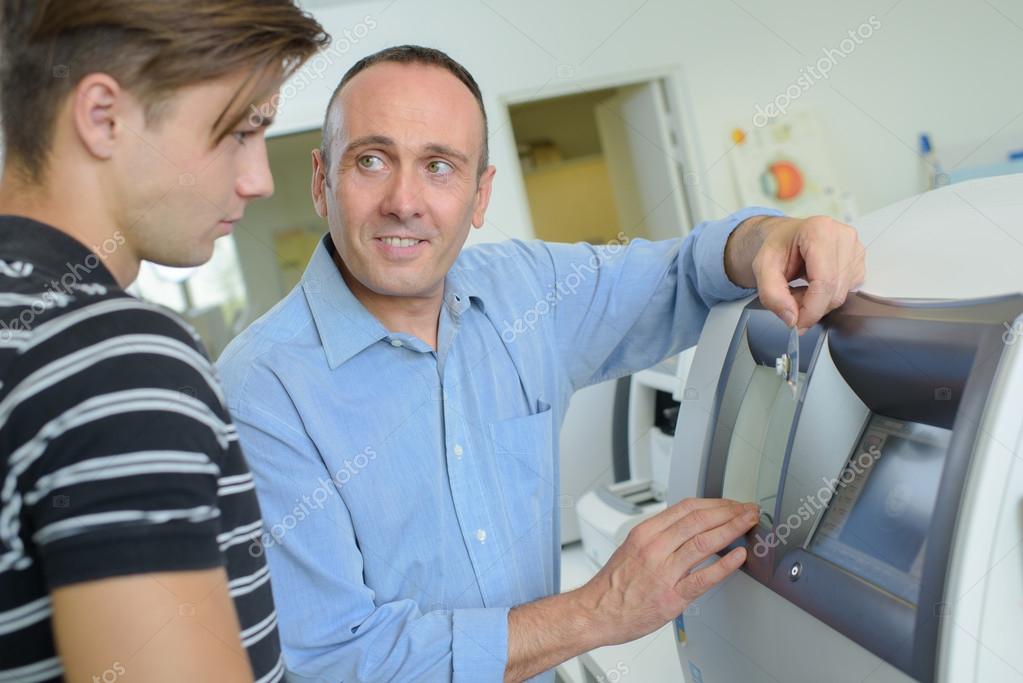 Man showing younger man how to use cash machine — Stock Photo ...