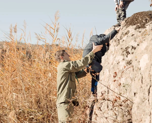 Scout helping a young boy rock climbing — Stock Photo © ampack #66236789