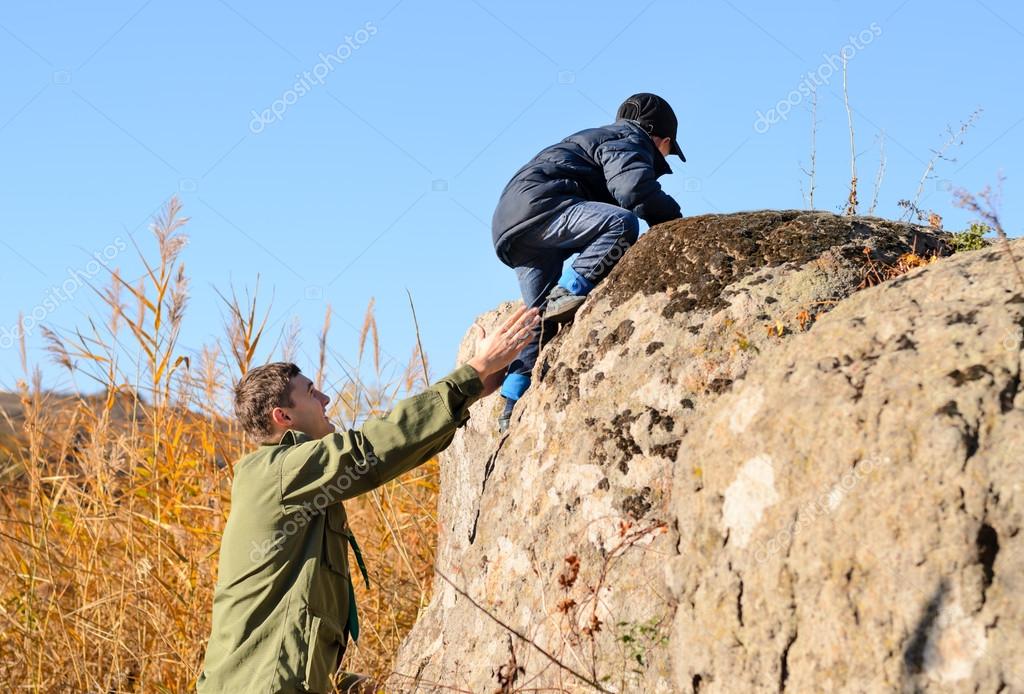 Scout helping a young boy rock climbing — Stock Photo © ampack #66236789