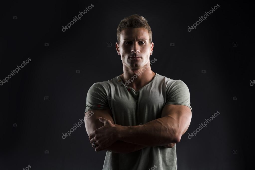 Handsome muscular fit young man on dark background with stern ...