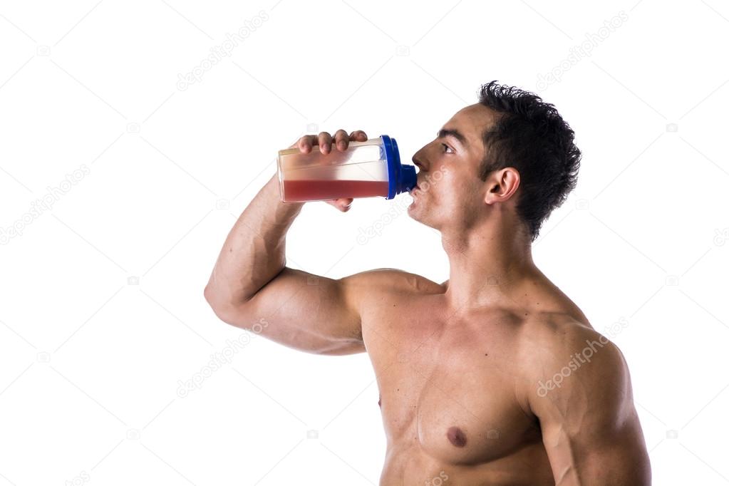 Muscular shirtless male bodybuilder drinking protein shake from blender ...