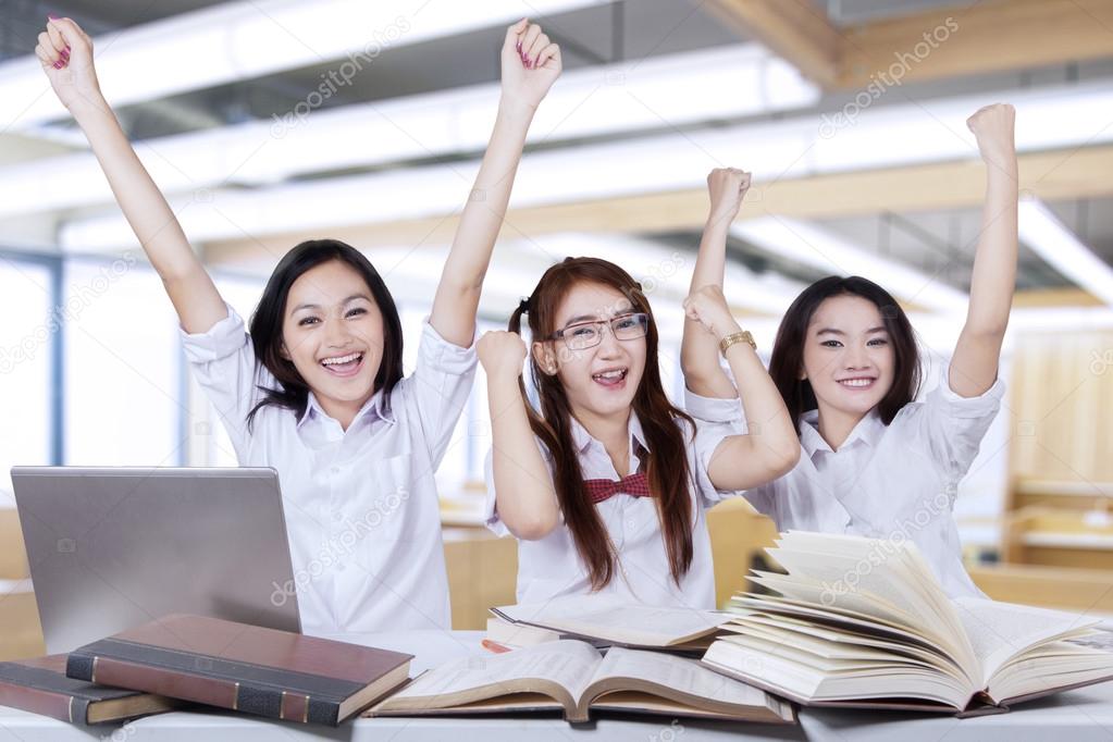 Three happy students raise hands in class — Stock Photo © realinemedia ...