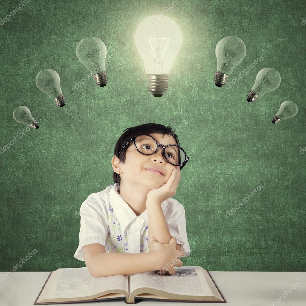 Child thinks inspiration under bright light bulb — Stock Photo ...