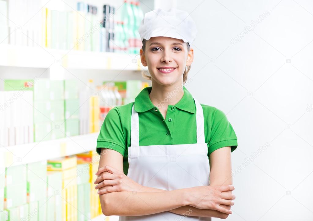 Smiling supermarket worker with shelf on background Stock Photo by ...