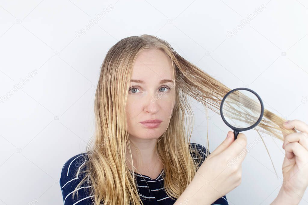 La chica mira delante de la lupa su cabello graso. cuero cabelludo ...
